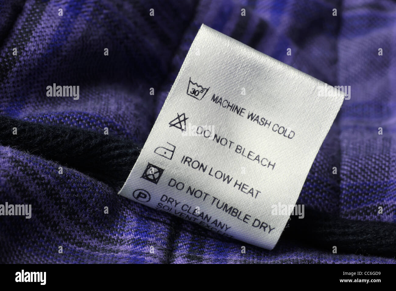 Label with laundry care symbols close-up on a blue scotch textile ...