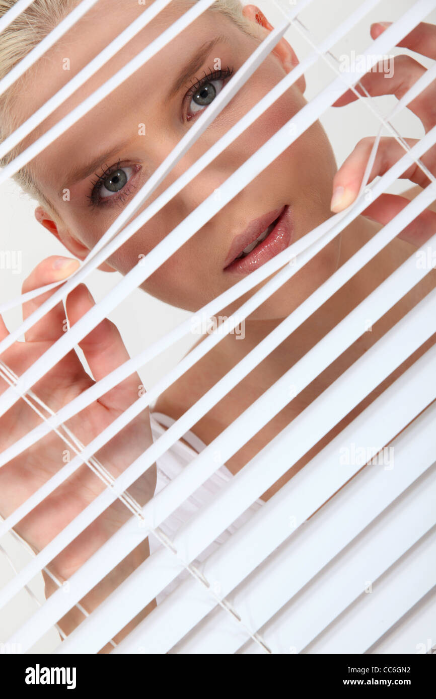 Woman peering through some blinds Stock Photo - Alamy