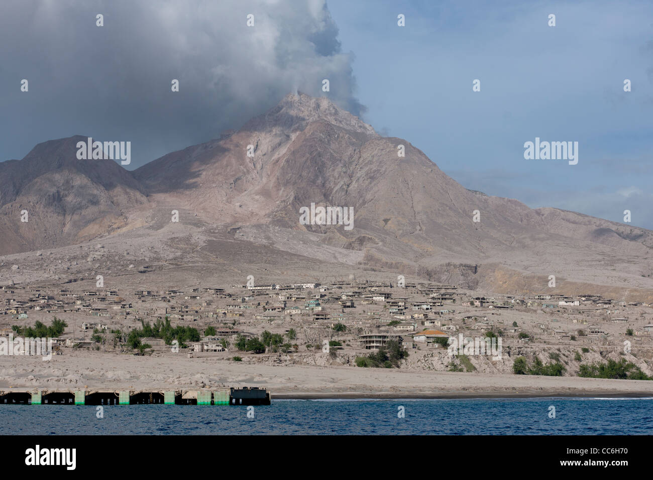 Smoking Soufriere Hills Volcano towering above the ruined former ...
