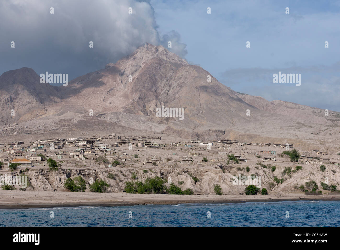 Smoking Soufriere Hills Volcano towering above the ruined former ...
