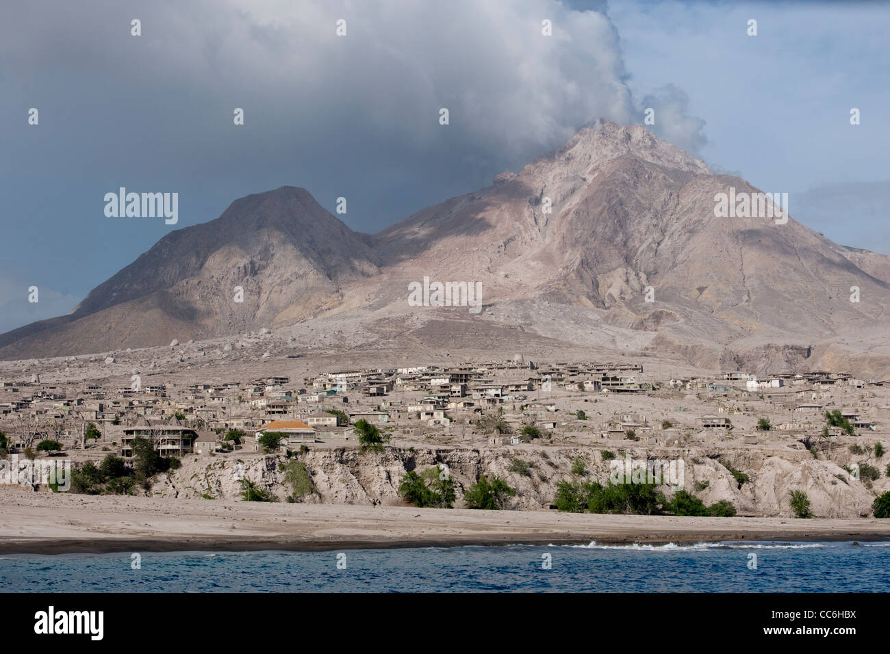 Smoking Soufriere Hills Volcano towering above the ruined former ...
