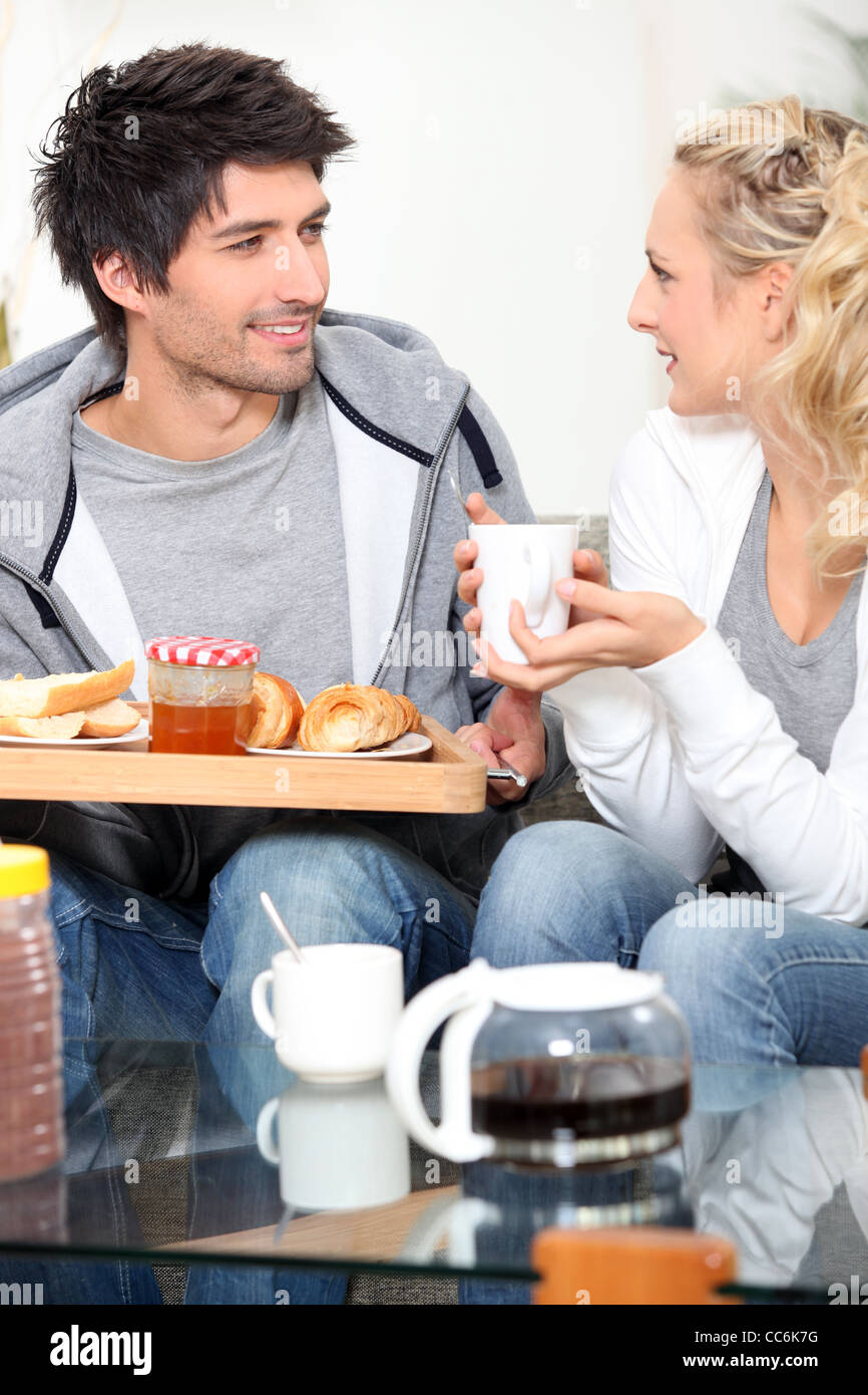 Couple having breakfast together on sofa Stock Photo - Alamy