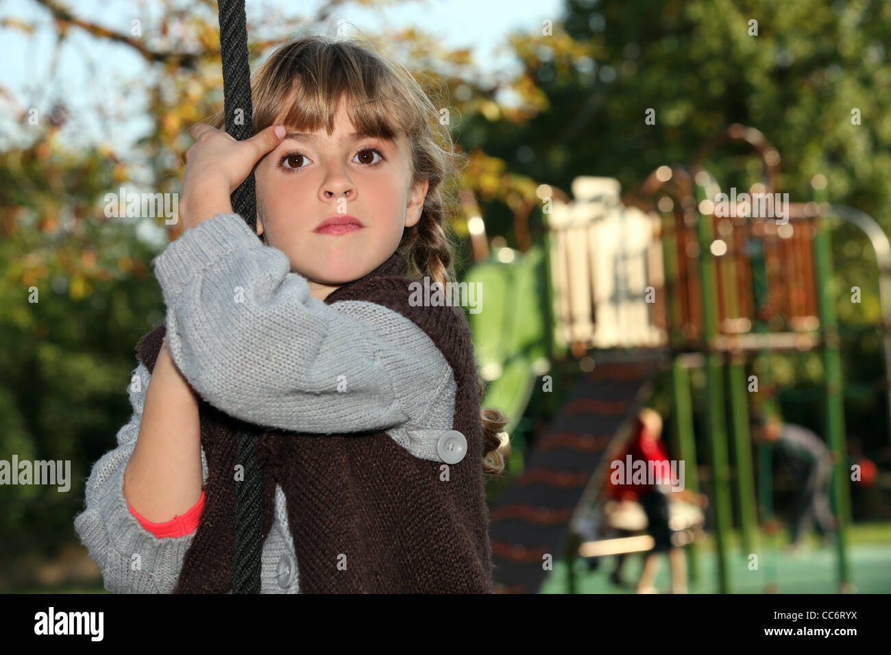 Girl holding onto a rope in a playground Stock Photo - Alamy