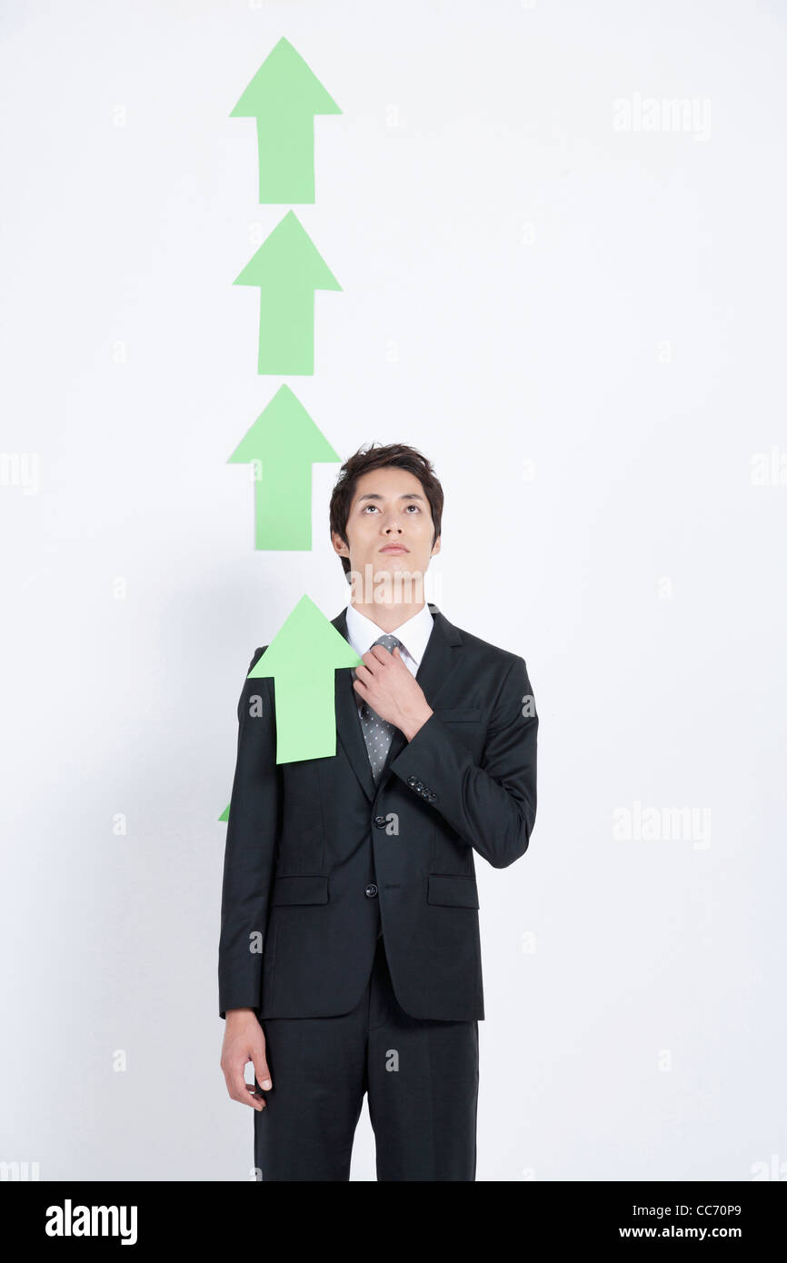 A man looking upon rising green arrows Stock Photo - Alamy