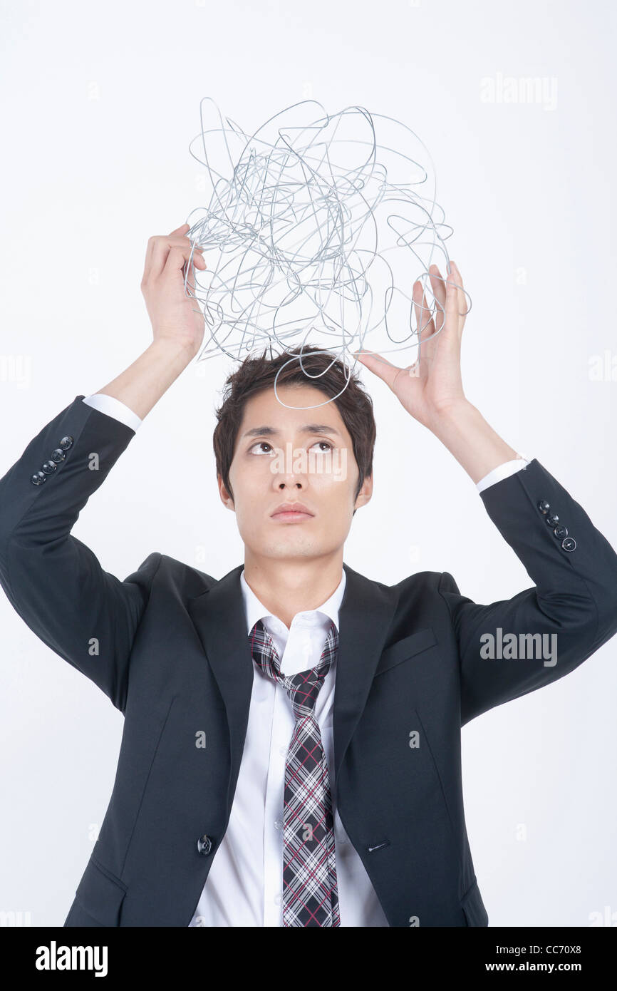 A stressful man holding up twisted wire ball Stock Photo - Alamy