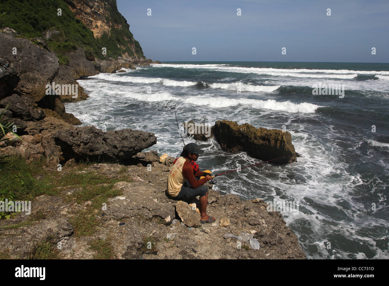 Teen boys fishing cliffs Parangtritis beach Java Indonesia indian ocean ...