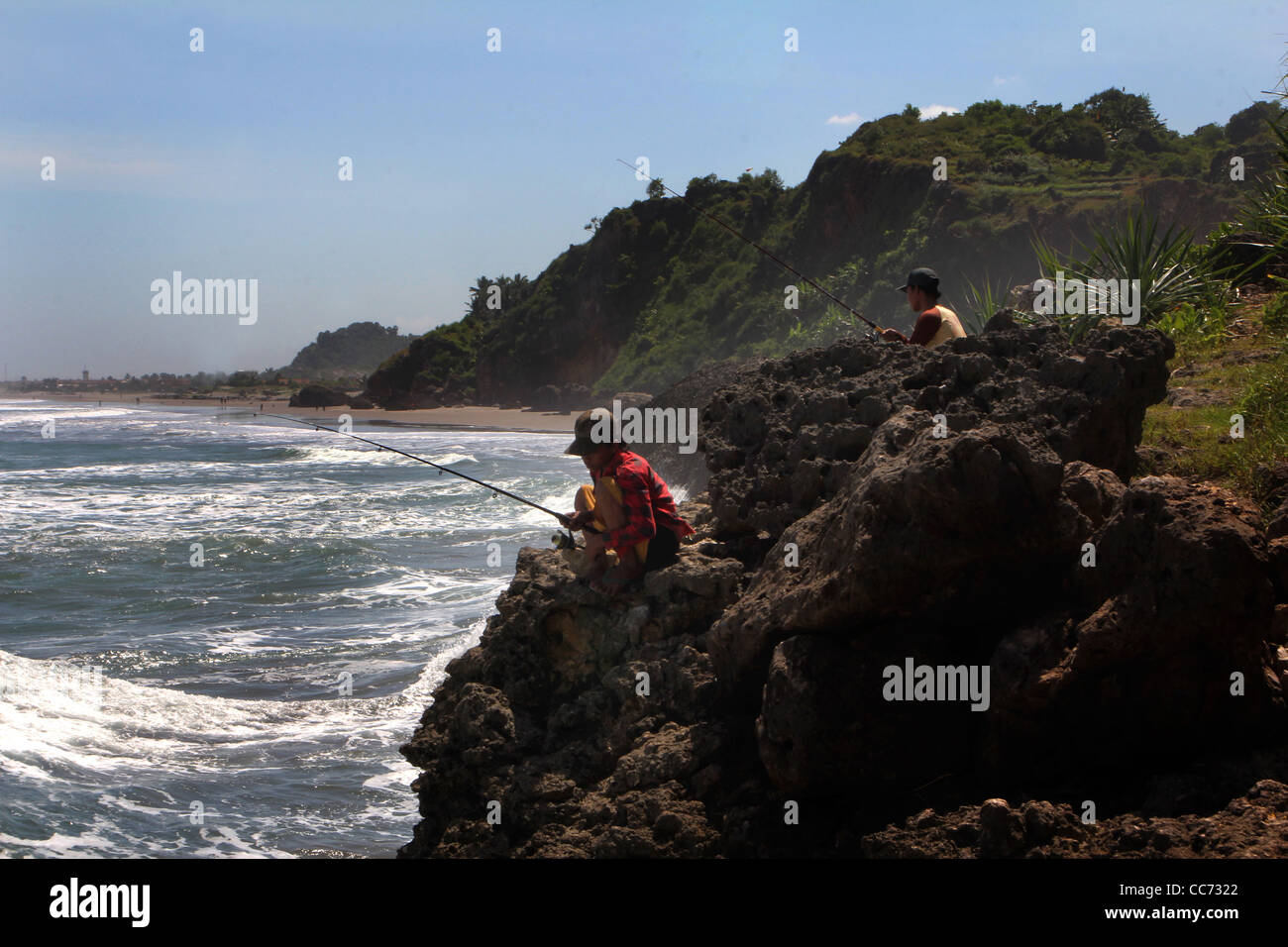 Teen boys fishing cliffs Parangtritis beach Java Indonesia indian ocean ...
