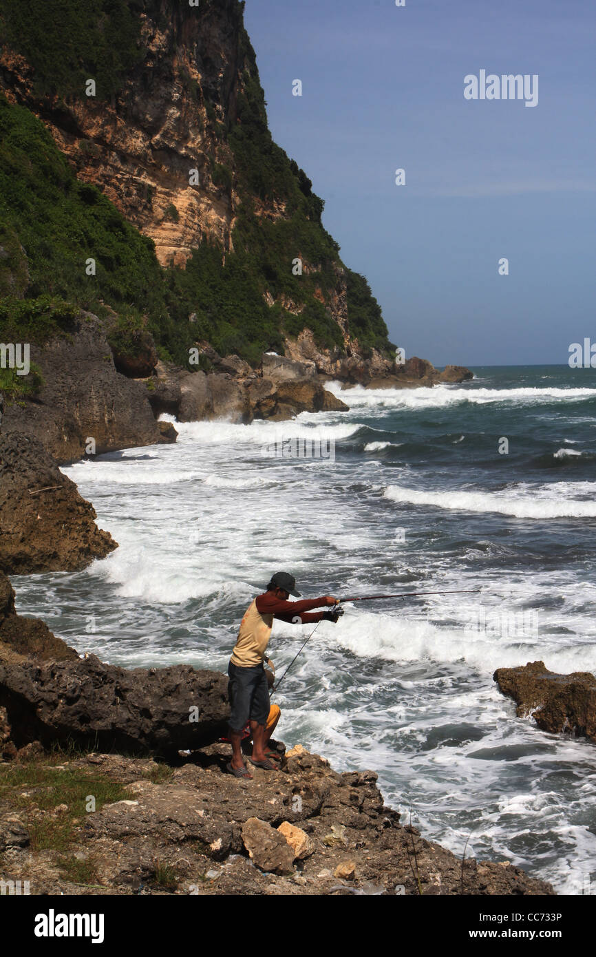 Teen boys fishing cliffs Parangtritis beach Java Indonesia indian ocean ...