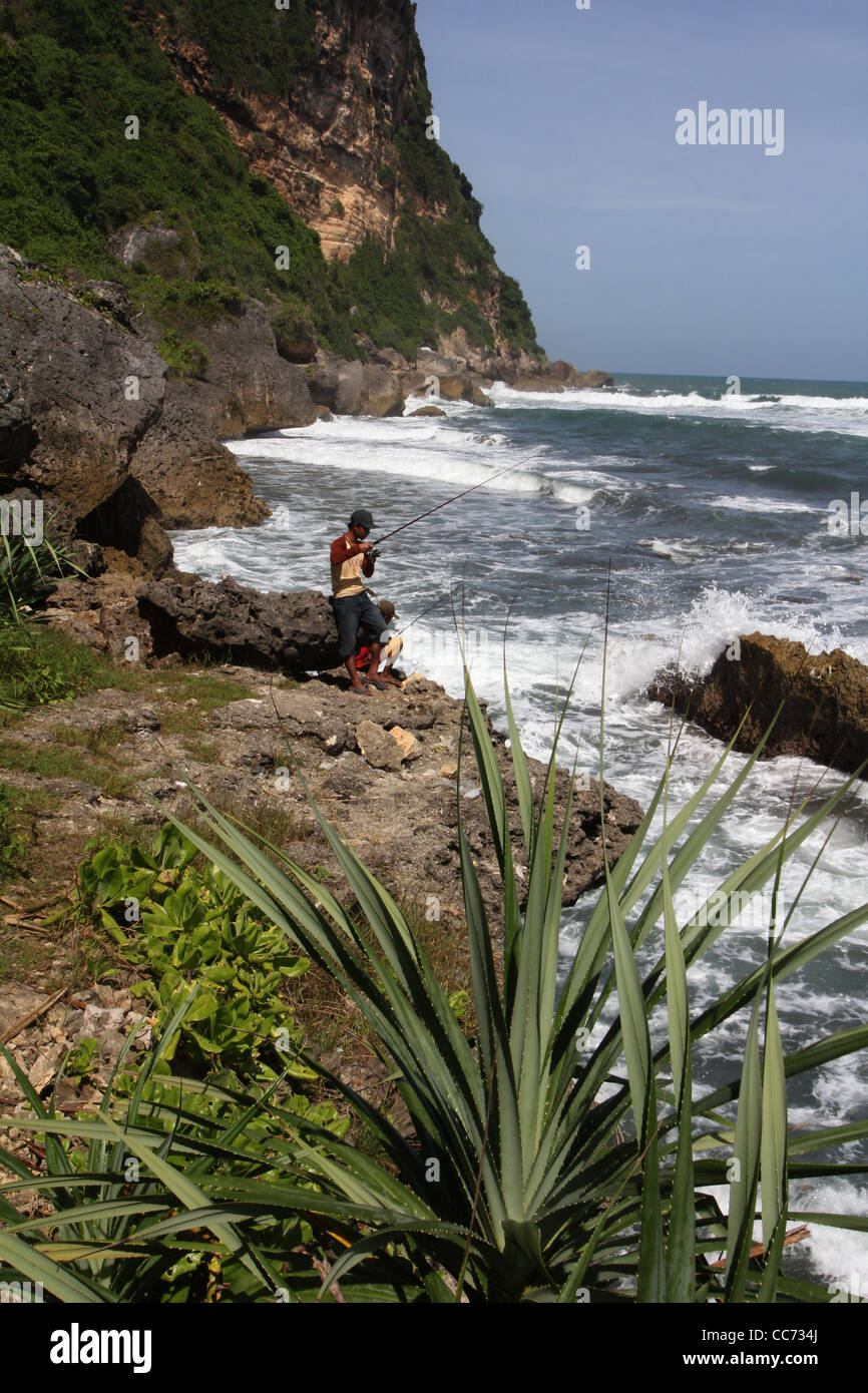 Teen boys fishing cliffs Parangtritis beach Java Indonesia indian ocean ...