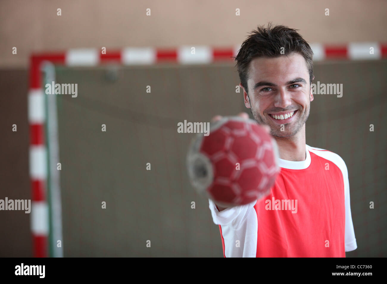 Man stood holding handball on indoor pitch Stock Photo - Alamy