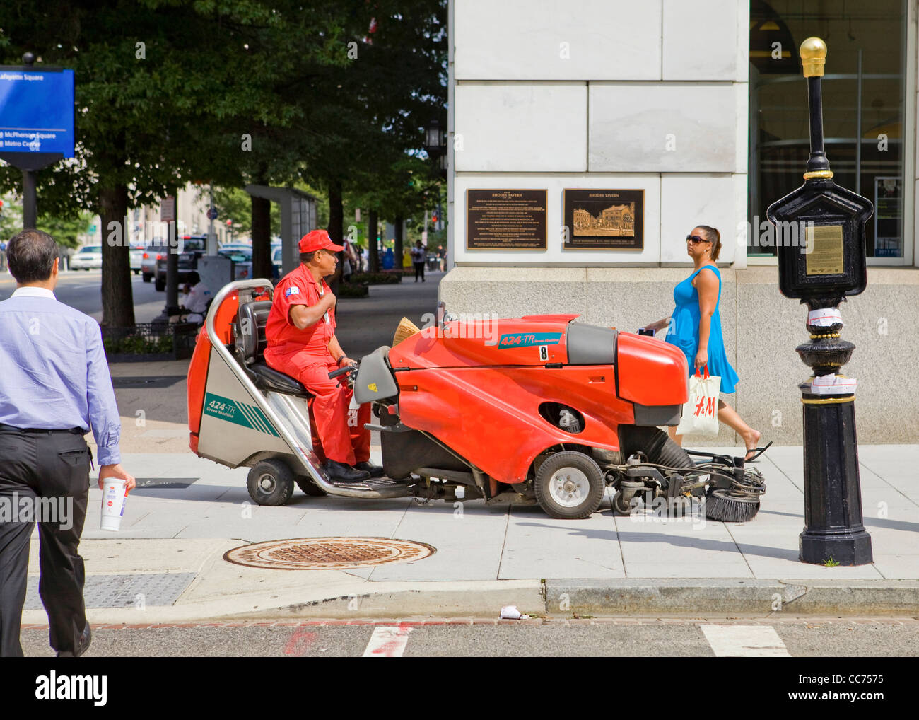 A man operating a vacuum sweeper on sidewalk Stock Photo - Alamy