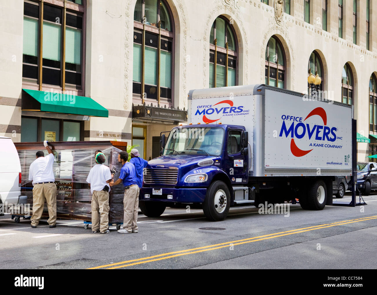 Office moving service workers move large furniture on dollies - USA ...