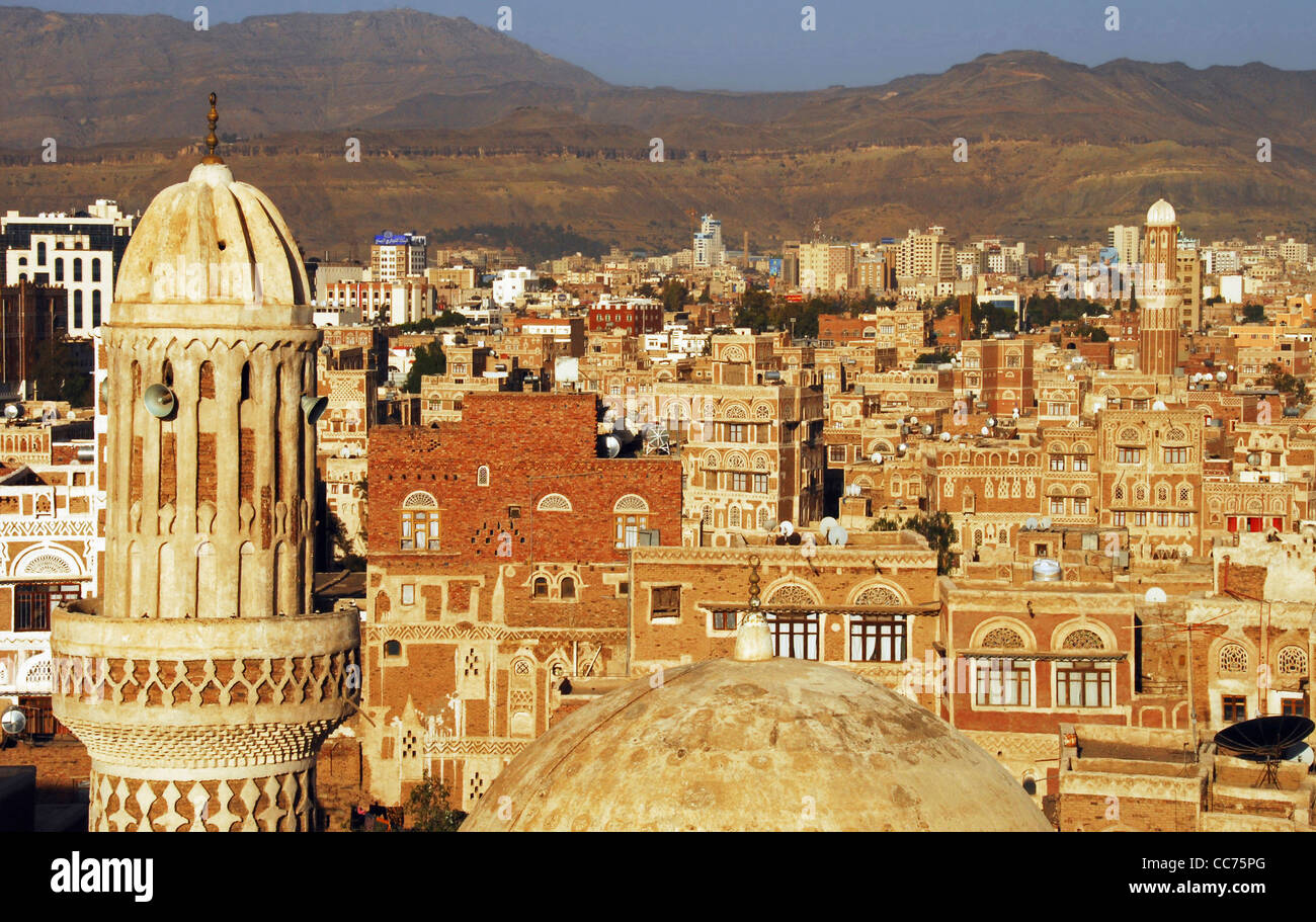 Yemen, Sanaa, historic mosque by buildings with mountain in the ...