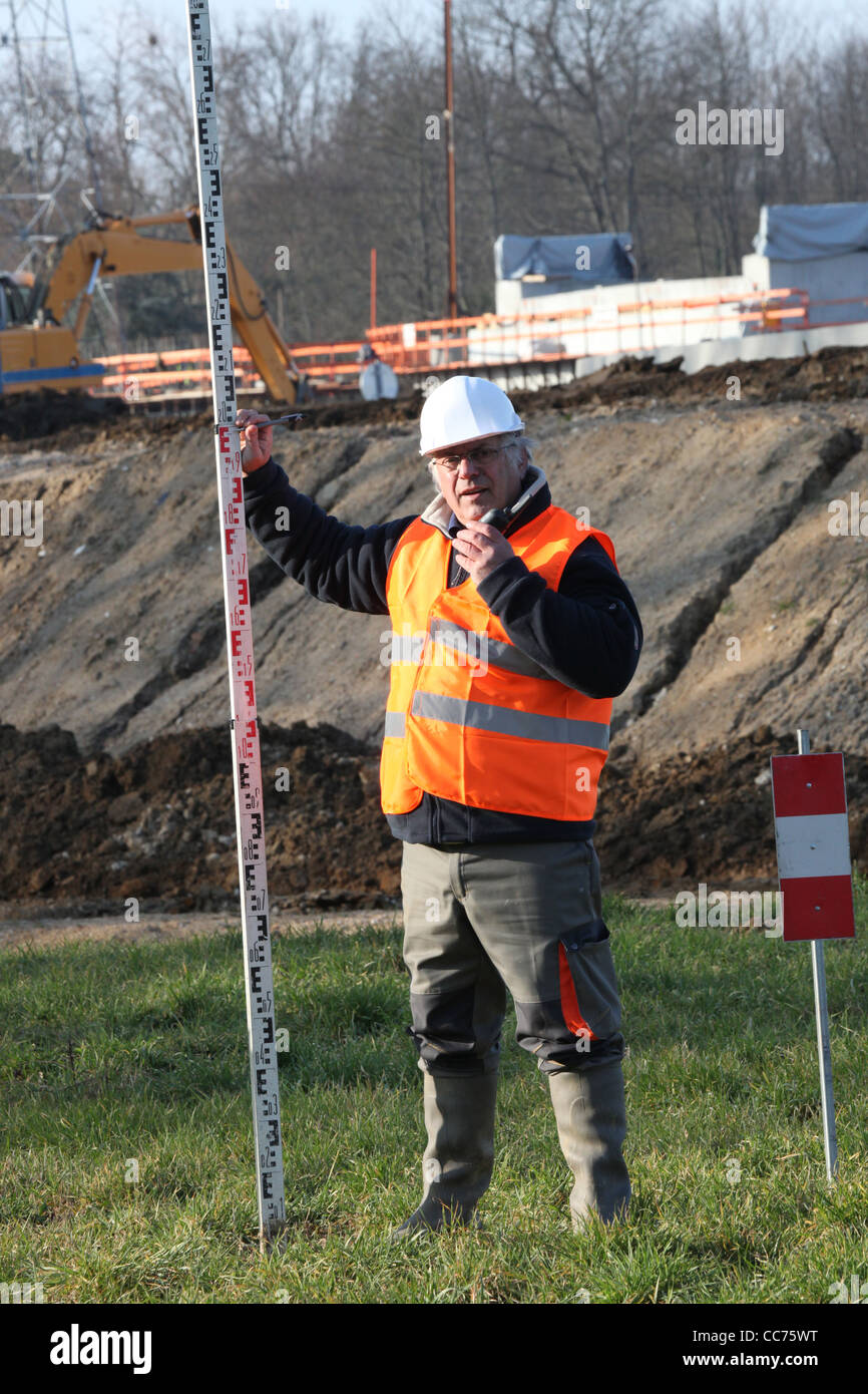 Man on construction site holding pole Stock Photo - Alamy