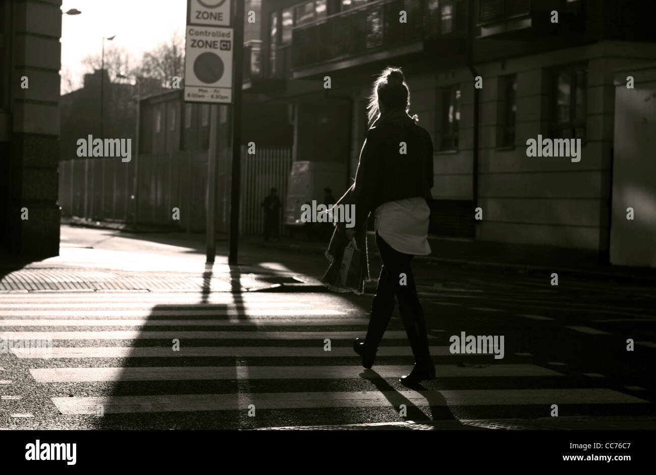 a female walks across a zebra crossing in London, photographed in sepia ...