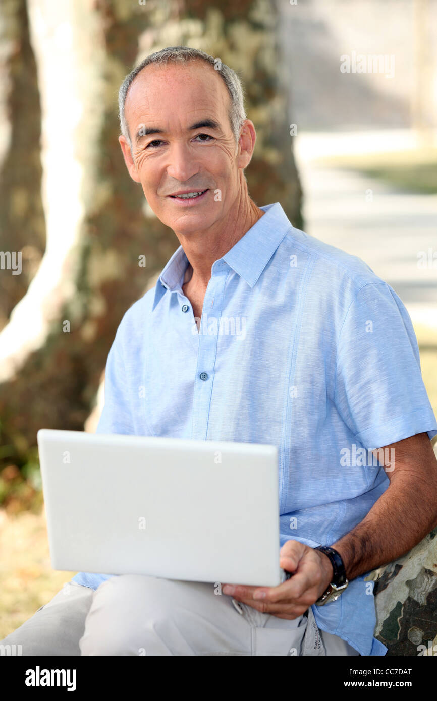 Grey haired man in park with laptop computer Stock Photo - Alamy