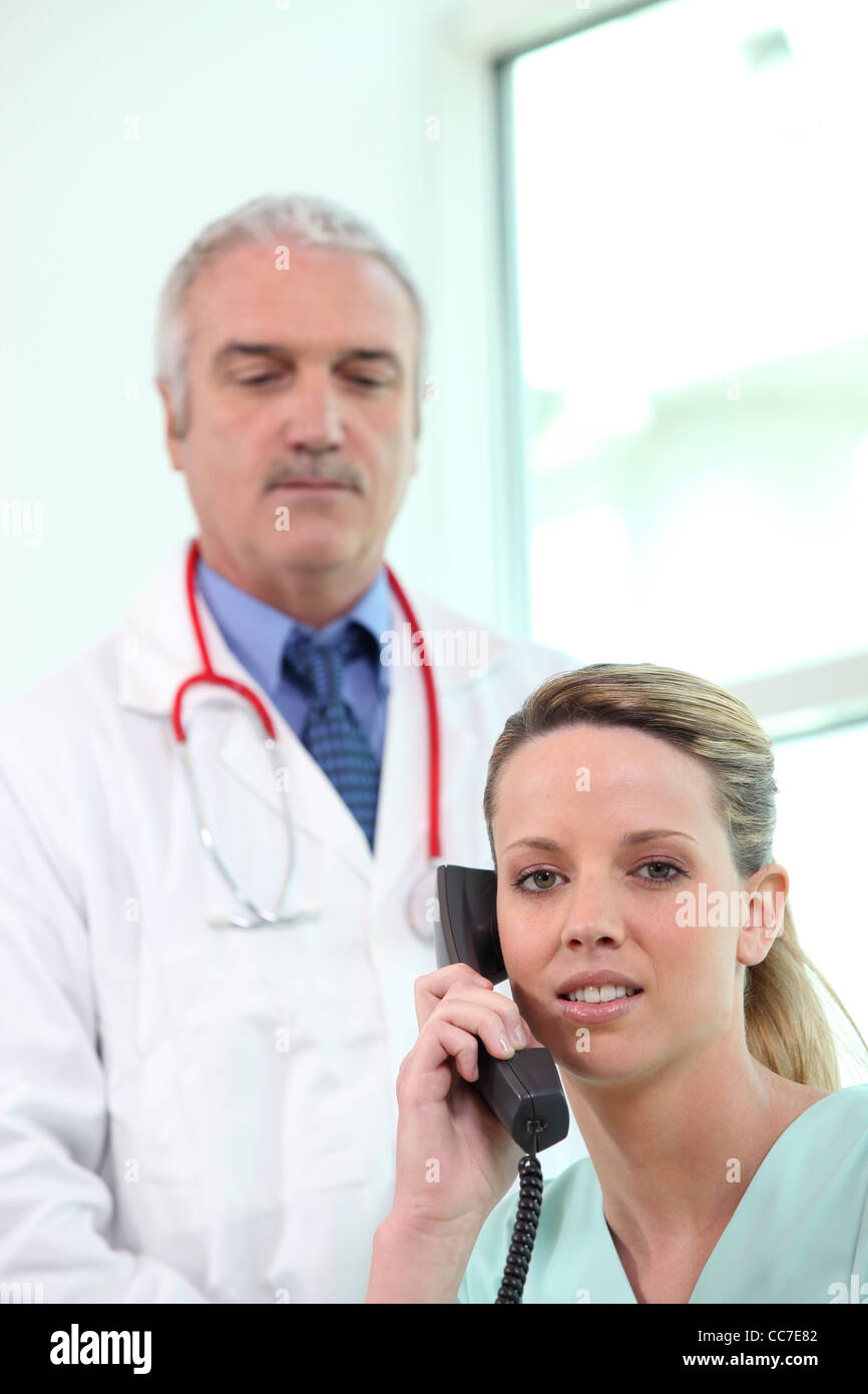 Nurse on the telephone whilst a doctor stands by Stock Photo - Alamy