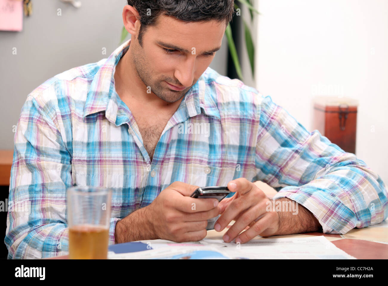 Man reading magazine and sending text message Stock Photo - Alamy