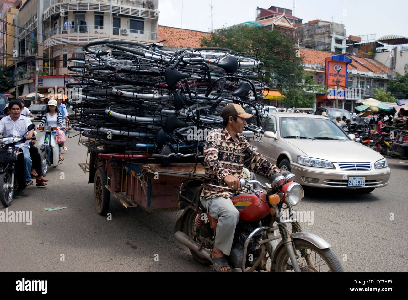 A man is pulling a load of bicycles in a cart with a Sanyang motorcycle ...