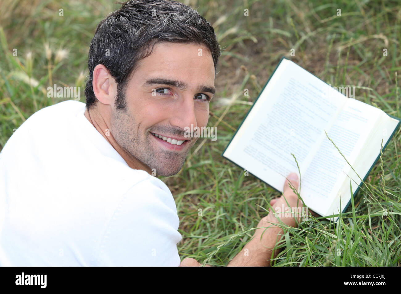 a man lying on grass is reading a book Stock Photo - Alamy