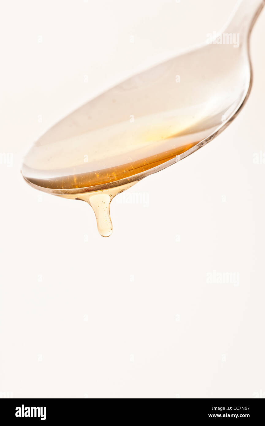 Spoon with dripping honey Stock Photo - Alamy