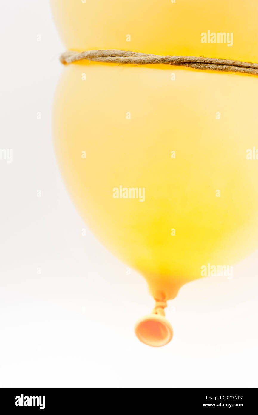 Yellow balloon squeezed by a string Stock Photo - Alamy
