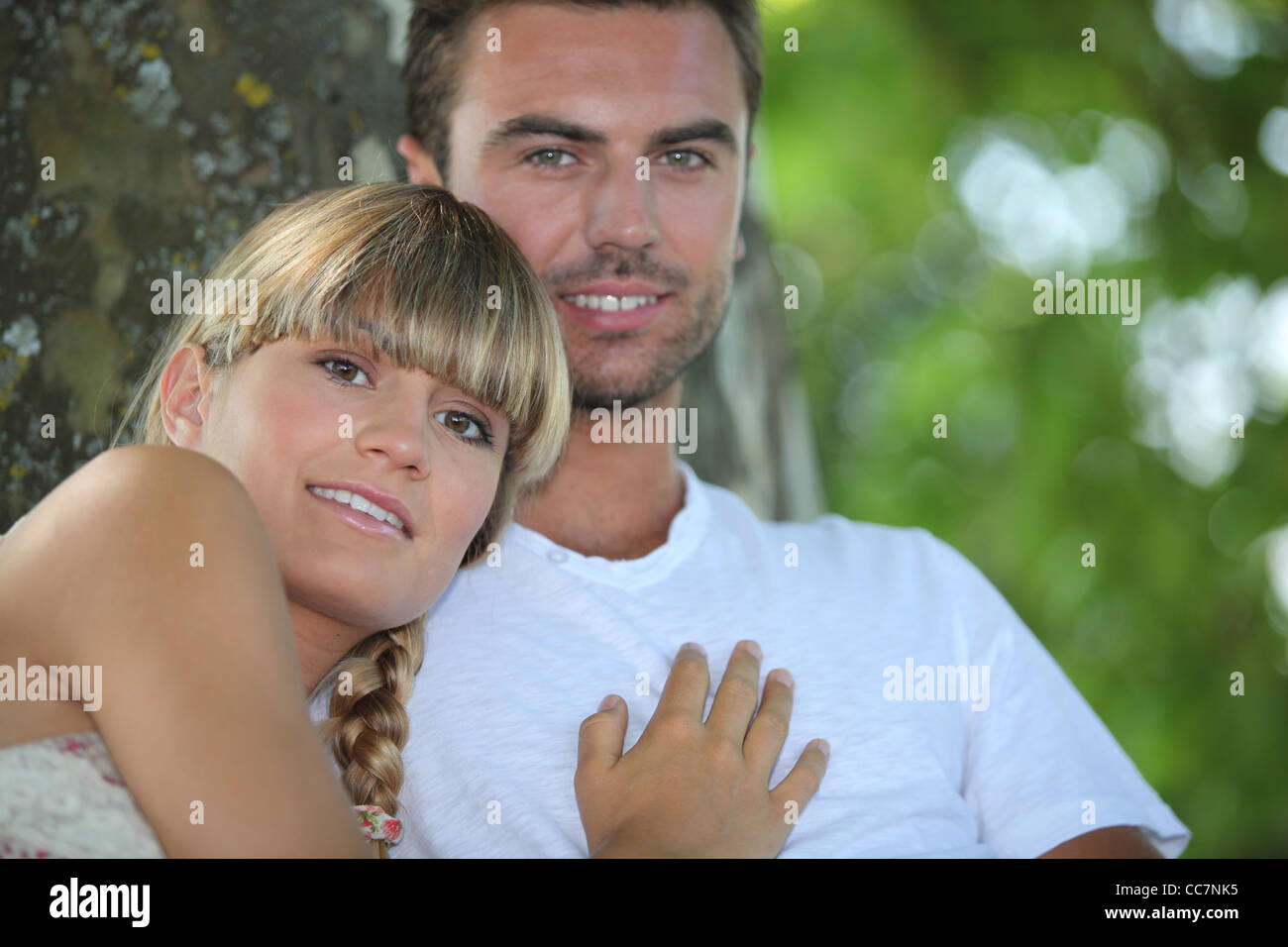 Couple sat by tree in park Stock Photo - Alamy