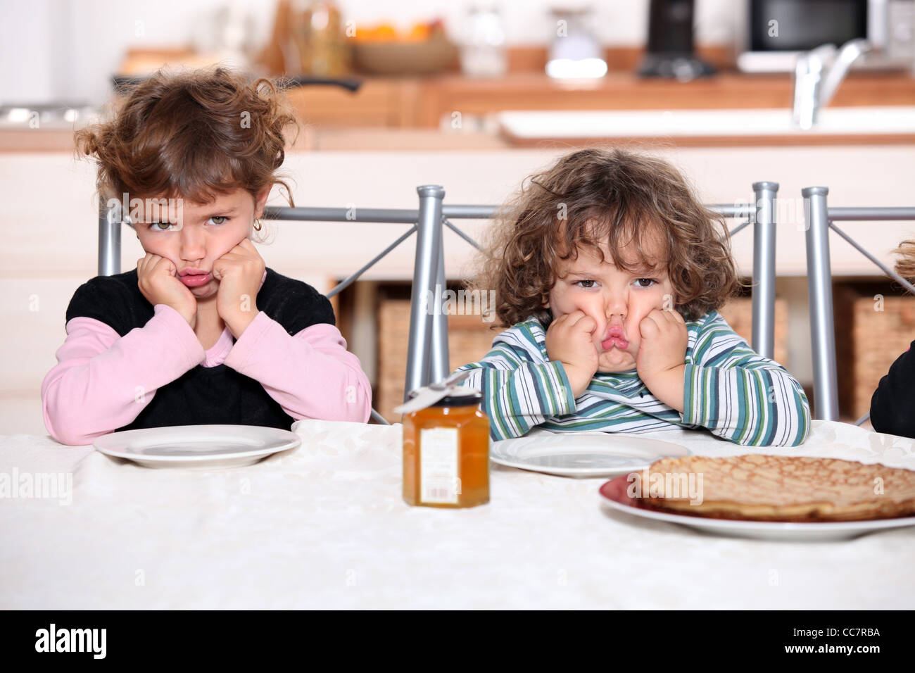 Kids pouting in the kitchen Stock Photo - Alamy