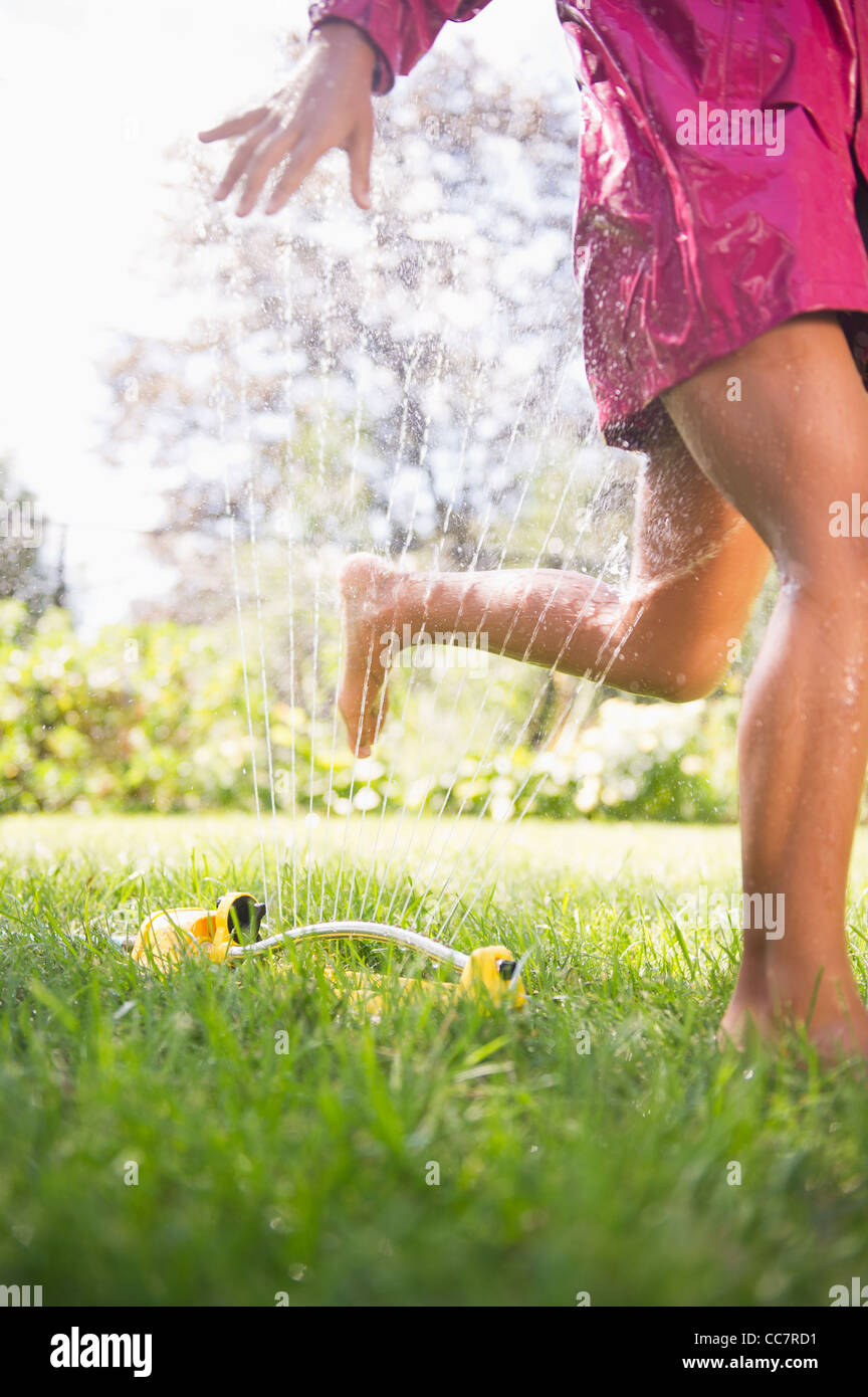 Hispanic girl running through sprinkler Stock Photo - Alamy
