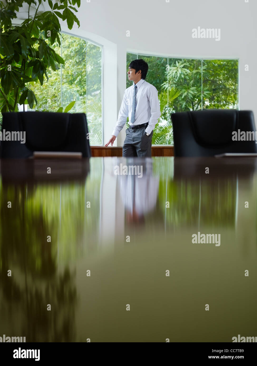 Pensive young asian business man looking out of the window in meeting ...