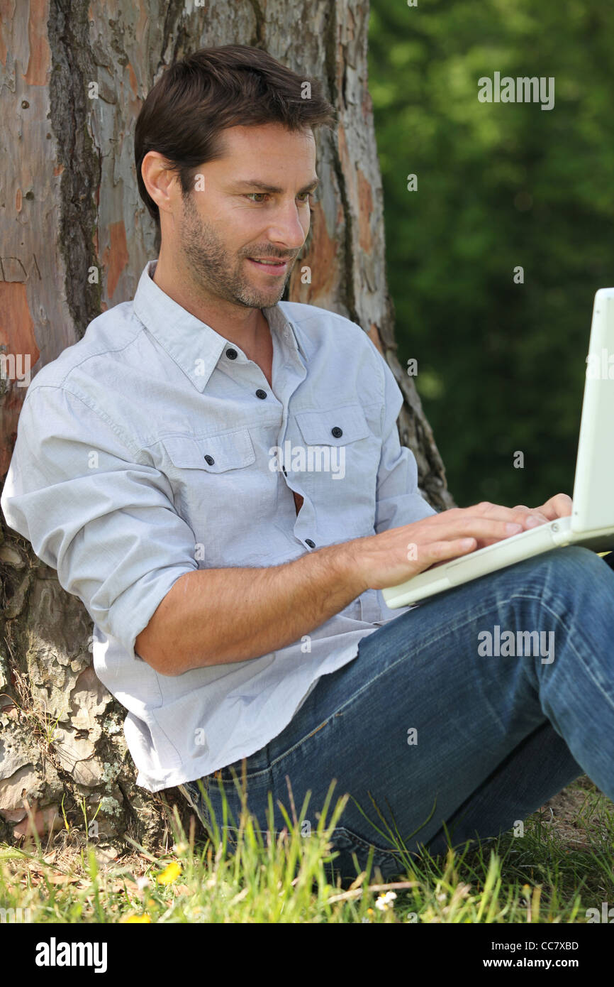 man sitting against a tree Stock Photo - Alamy