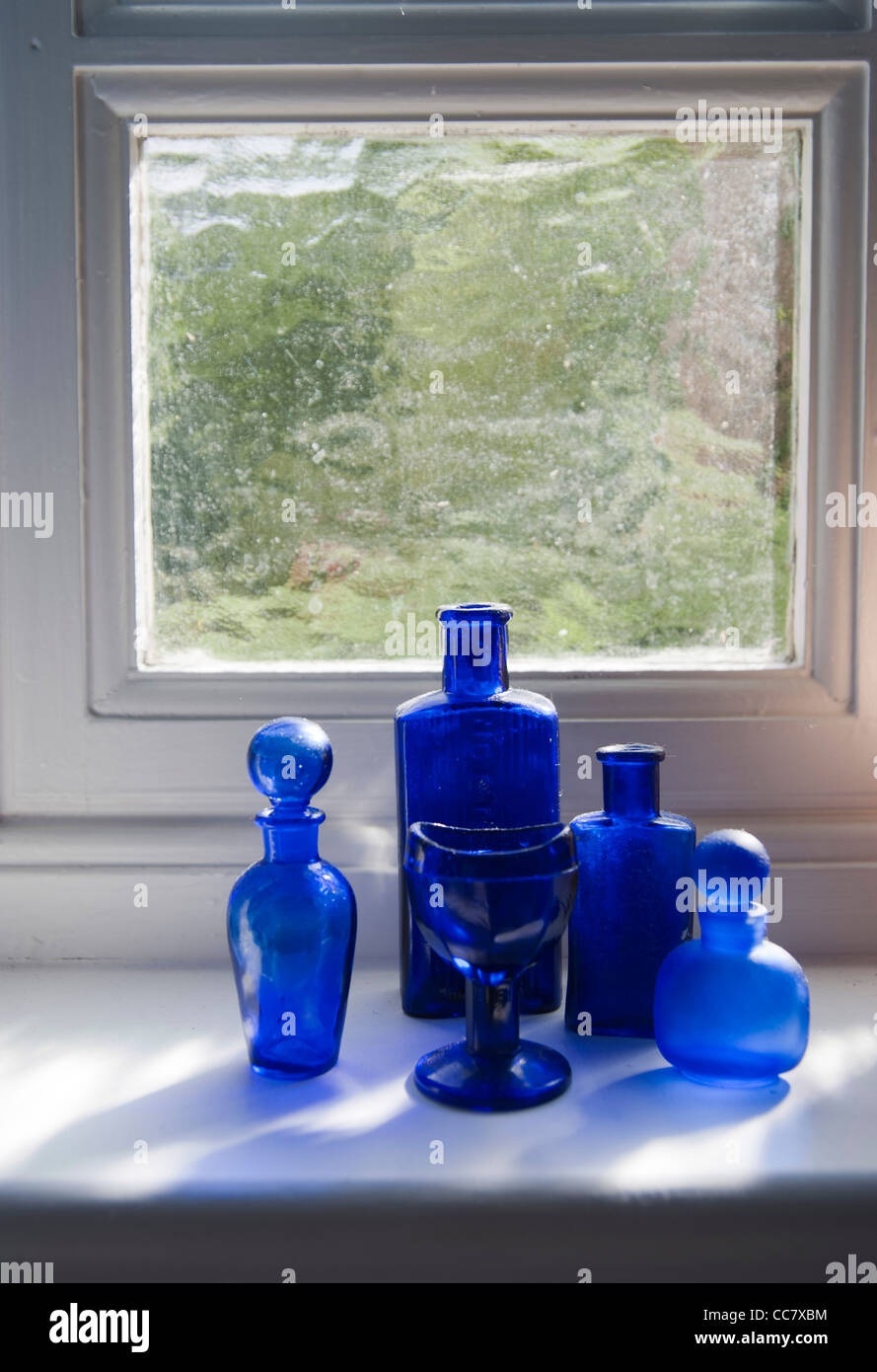 Cobalt blue bottles displayed on a window sill Stock Photo - Alamy