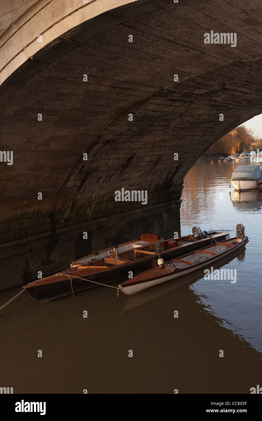 Boats moored in River Thames under the arches of Richmond Bridge ...