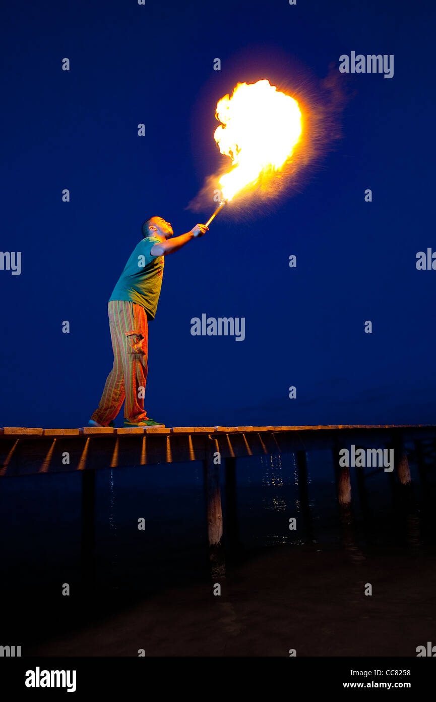 Male fire eater performing on the beach pier, Alcudia at dusk, Majorca ...