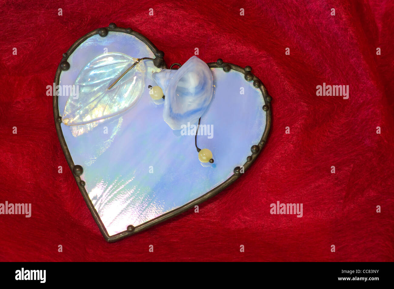 heart shaped opaque glass ornament with metal trim adorned with leaf ...