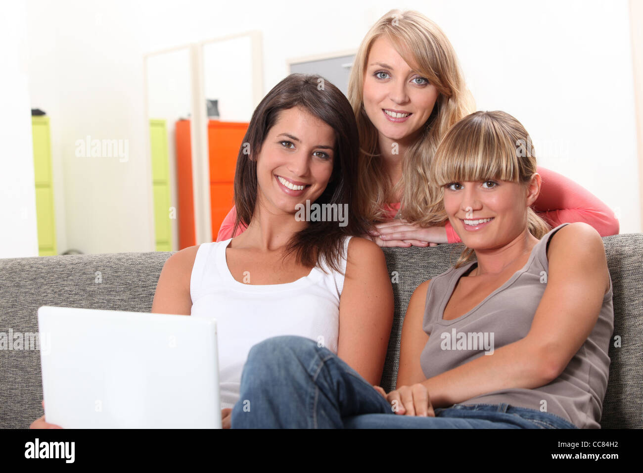 Three girls relaxing at home in front of laptop computer Stock Photo ...