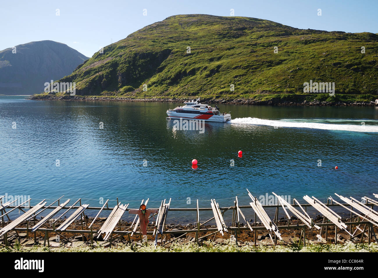 Blue bay of Akkarfjord with speedboat and wooden rackes Stock Photo - Alamy