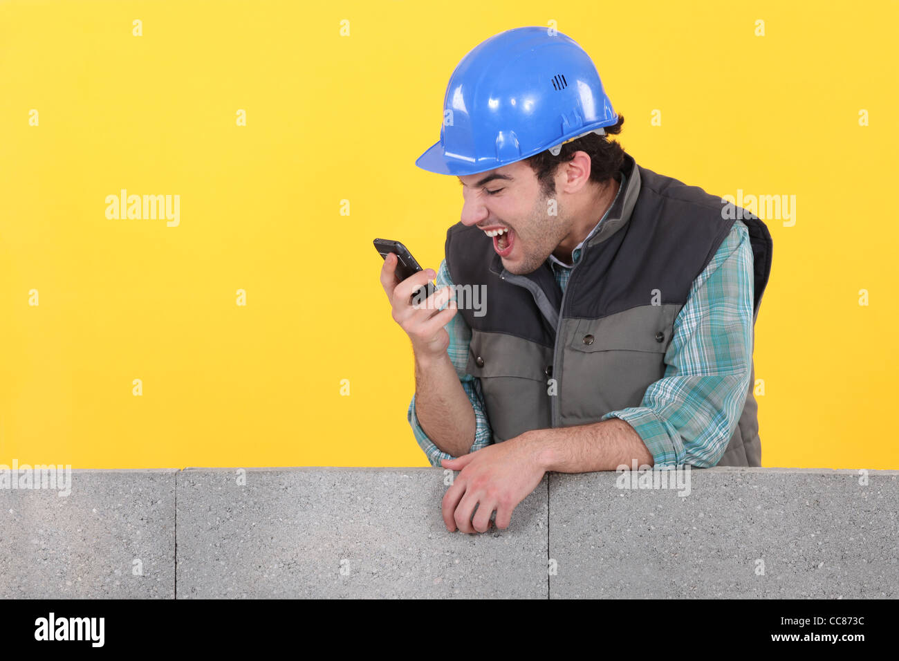 Builder shouting down his cellphone Stock Photo - Alamy