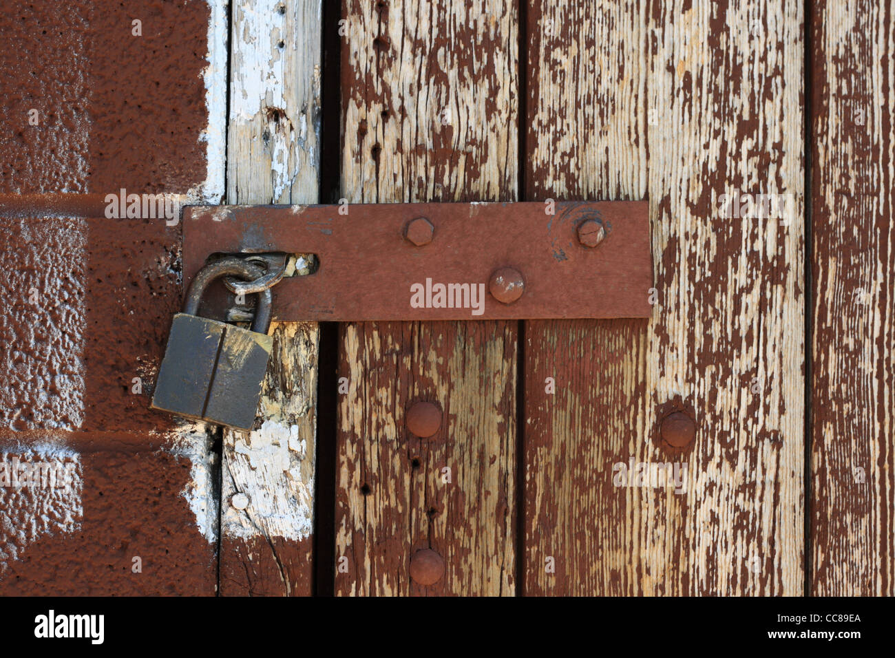 padlocked hasp on weathered painted brown wood door Stock Photo - Alamy