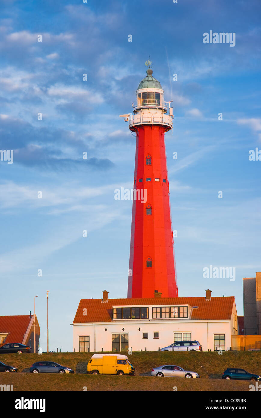Red lighthouse at the beach in evening light with blue sky background ...
