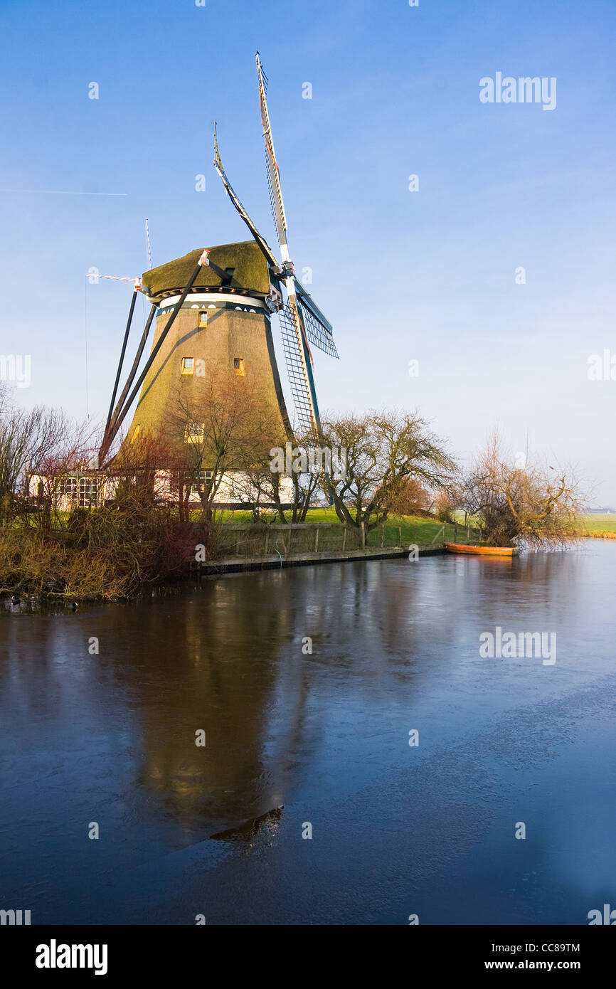 Dutch windmill in sunny frozen polder landscape with blue sky- vertical ...