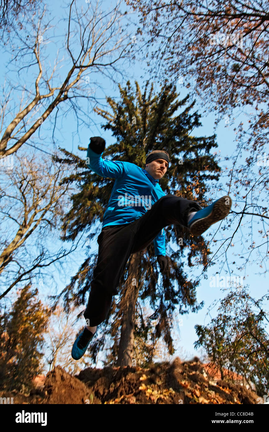 Young man jumping over a hole in a forest Stock Photo - Alamy