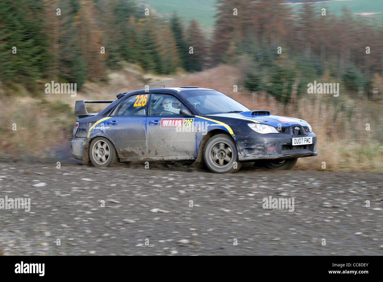 gravel sprays from a rally cars wheels as it passes Stock Photo - Alamy