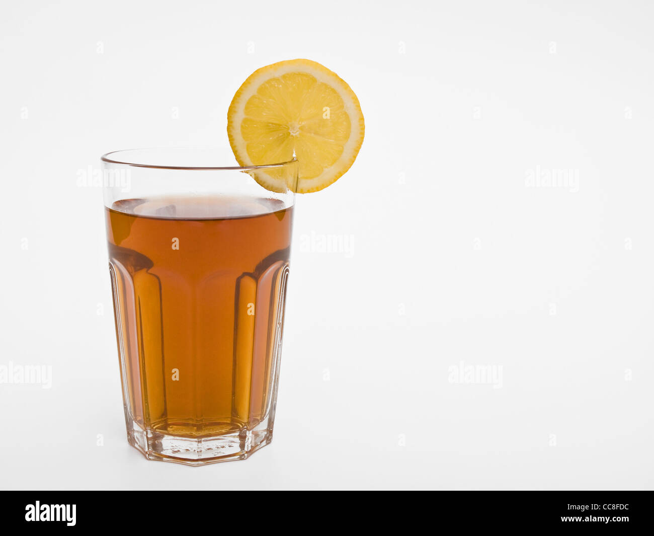 a glass with iced tea, a slice of lemon is on the brim of the glass ...