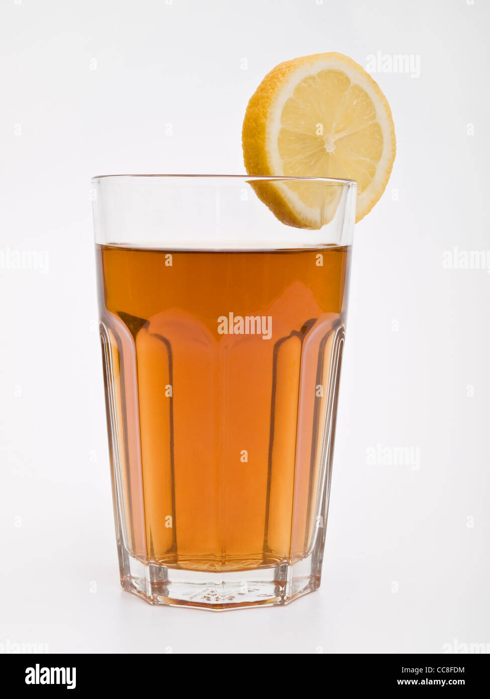 a glass with iced tea, a slice of lemon is on the brim of the glass ...