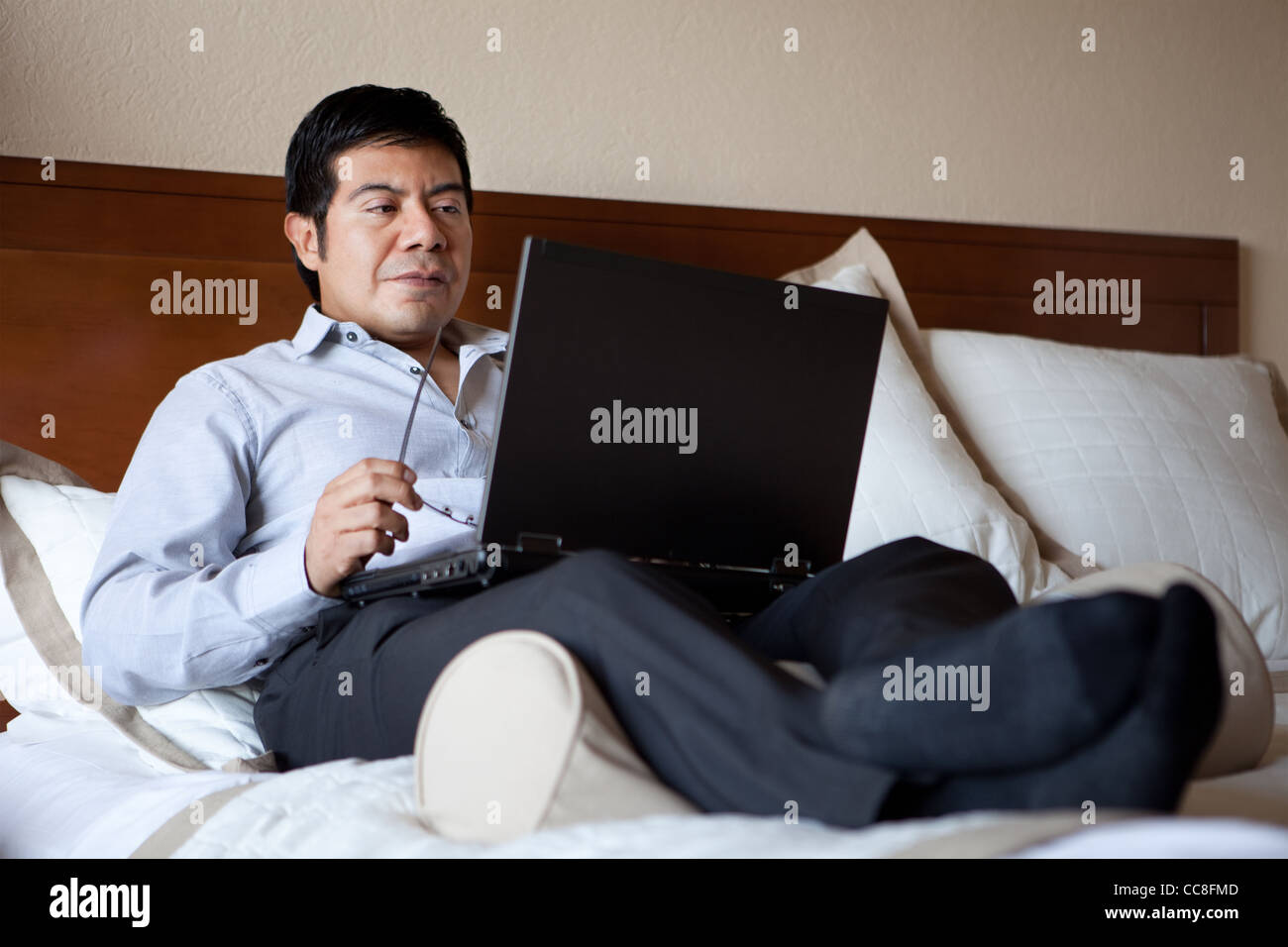Serious hispanic businessman using laptop in his hotel room Stock Photo ...