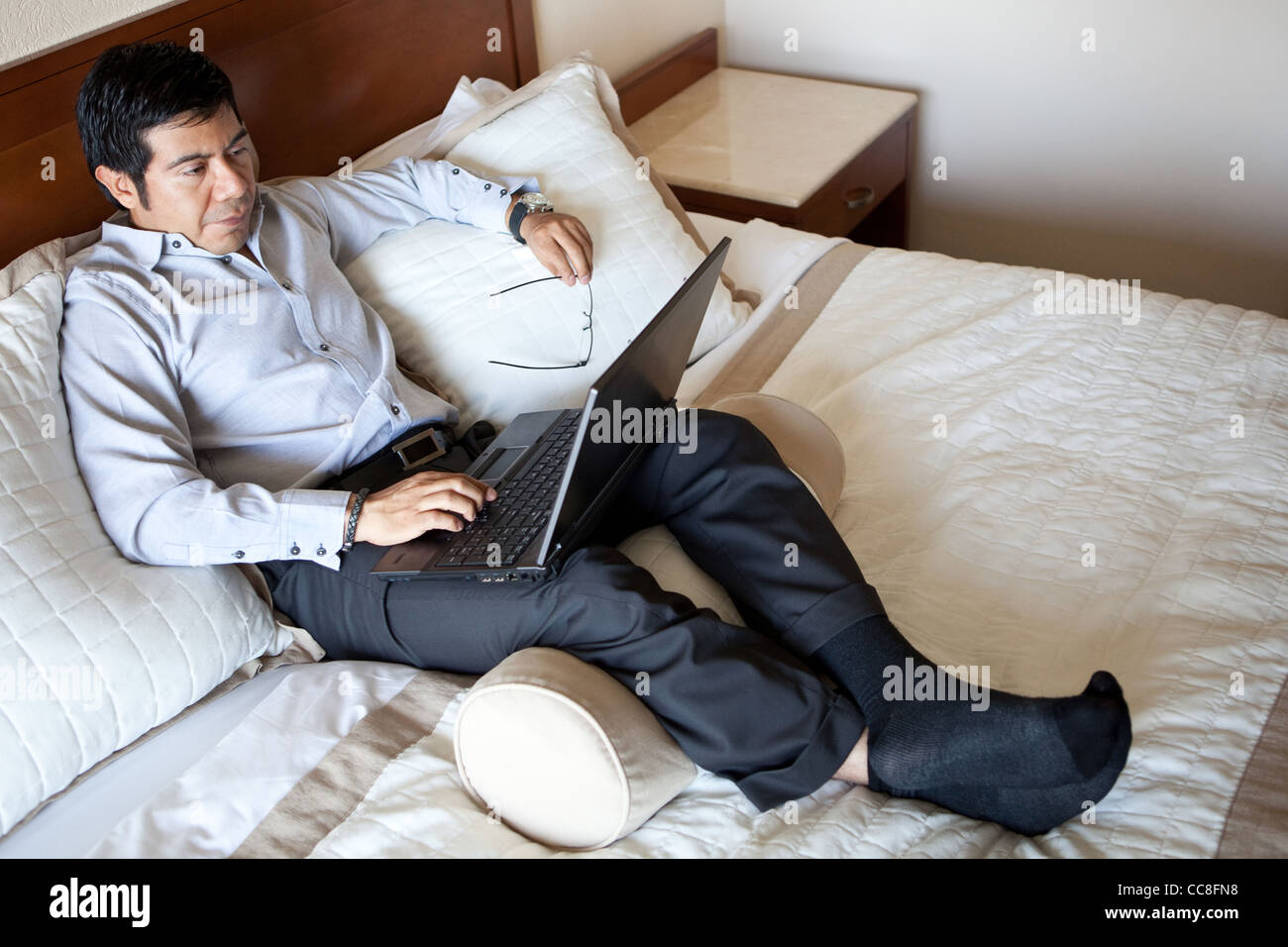 Serious hispanic businessman using laptop in his hotel room Stock Photo ...