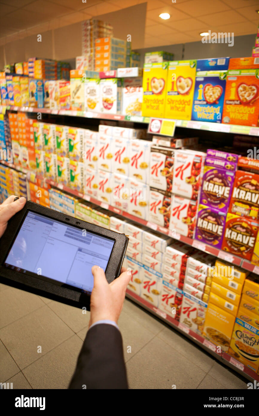 Handheld tablet at a supermarket shelf for order taking of cereals held ...