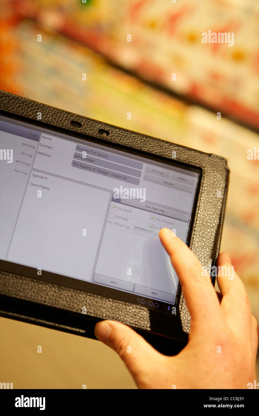 Handheld tablet at a supermarket shelf for order taking of cereals held ...