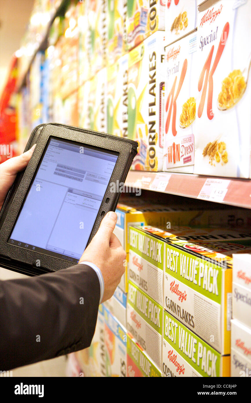 Handheld tablet at a supermarket shelf for order taking of cereals held ...